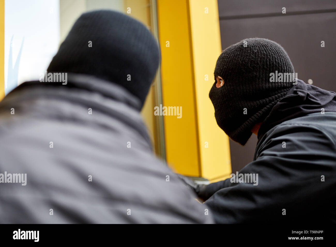 Two burglars quietly explore a house through a window for a burglary ...