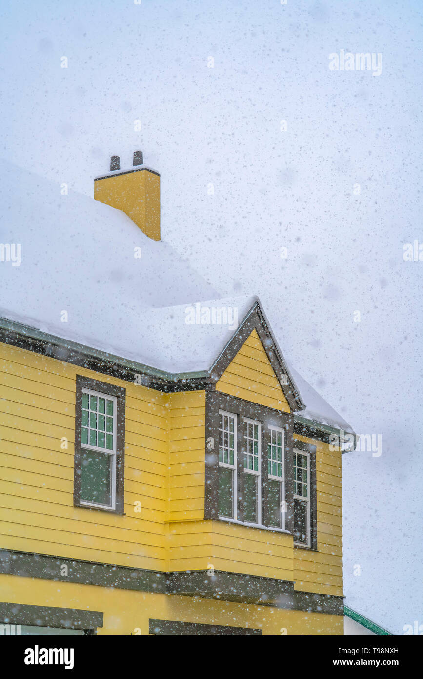 Snowy yellow home viewed through falling snow Stock Photo - Alamy