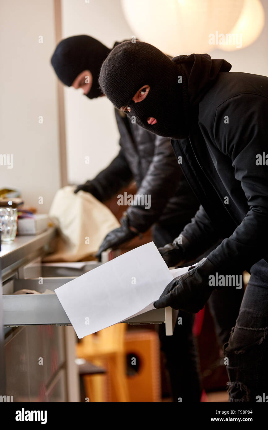 Two burglars look in drawers for prey during a burglary in a house ...