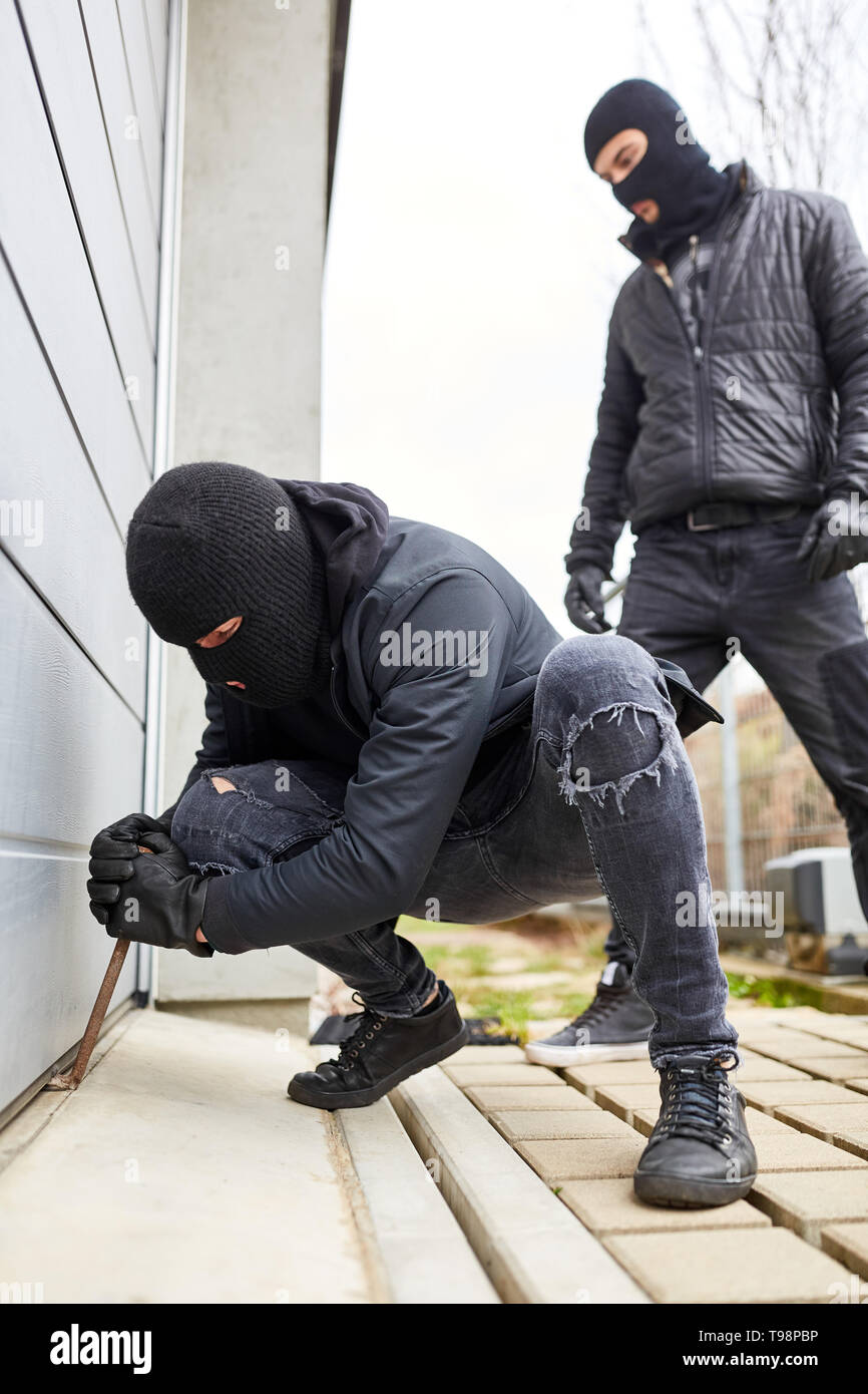 Burglars pry open the gate of a garage or warehouse with a crowbar ...