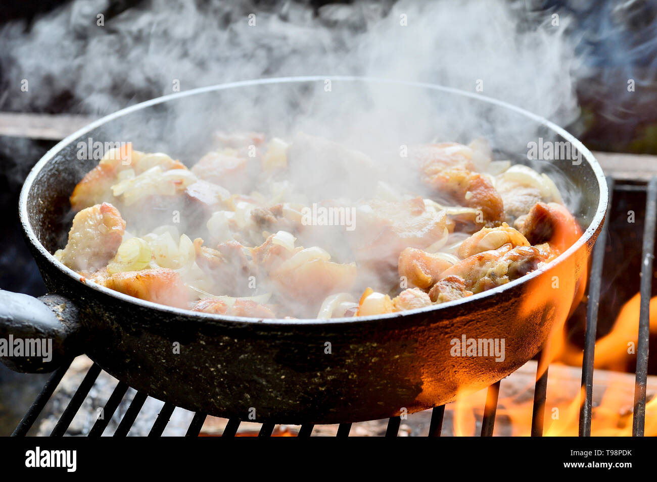 Cooking meat in a pan with onions on the grill. Fried pork Stock Photo ...