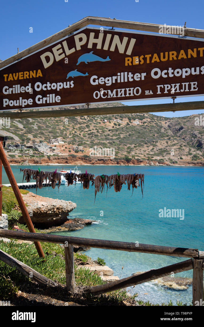 Greek taverna with octopus hanging outside overlooking secluded bay in ...