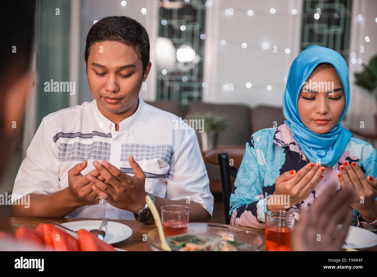 together pray before meals, a fast breaking meal served on a table in ...