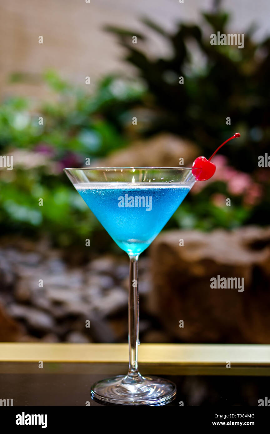 Blue cocktail decorated with red cherry in Martini glass Stock Photo ...