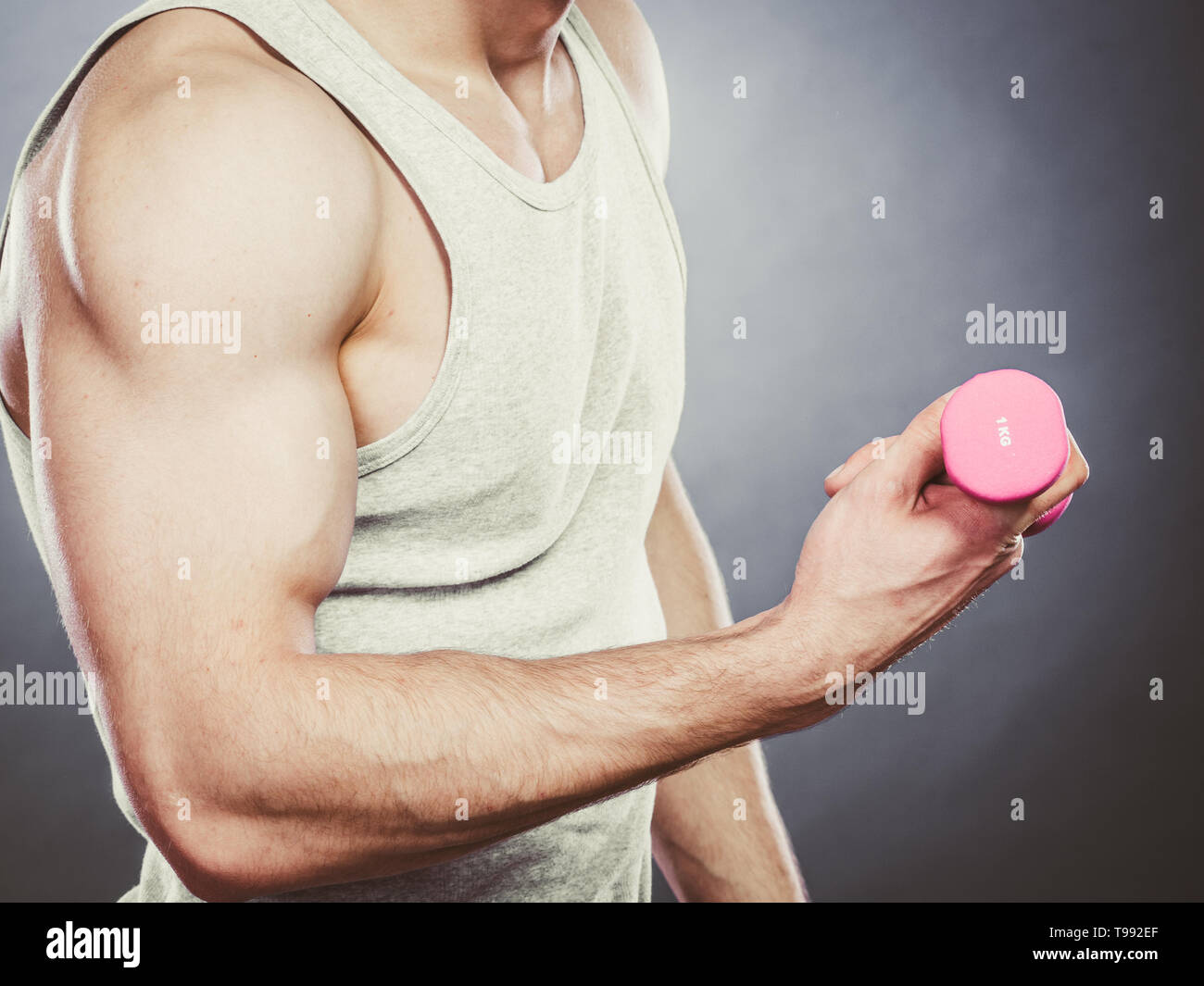 Funny sporty fit man lifting light dumbbell weight. Closeup of muscular ...