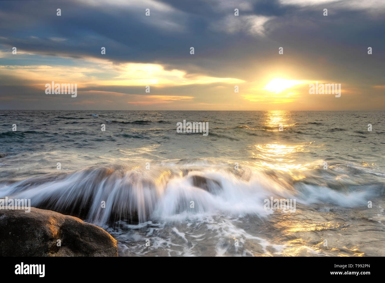wave hit rock at sunset Stock Photo - Alamy