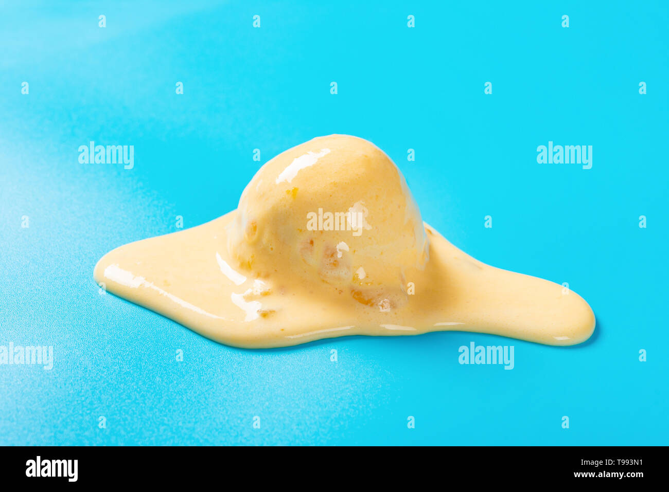 side view mango flavor ice cream ball in a melting process on blue ...