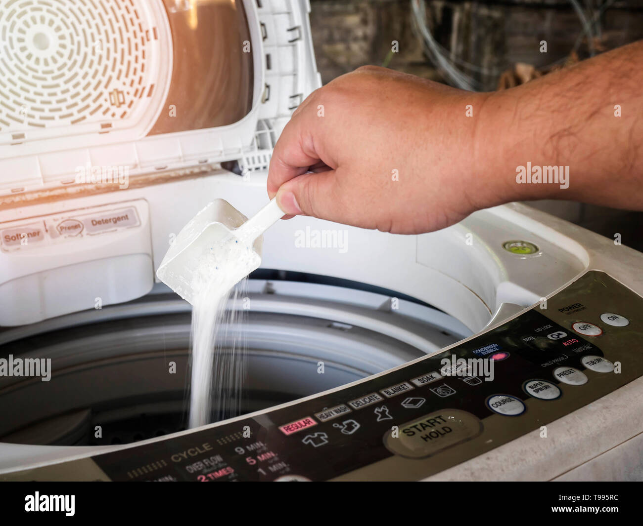 A man pouring laundry detergent or washing powder into the washing ...