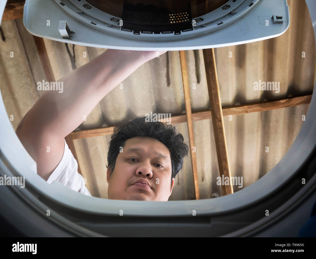 Man open the washing machine door, he doing Laundry.Inside view of ...