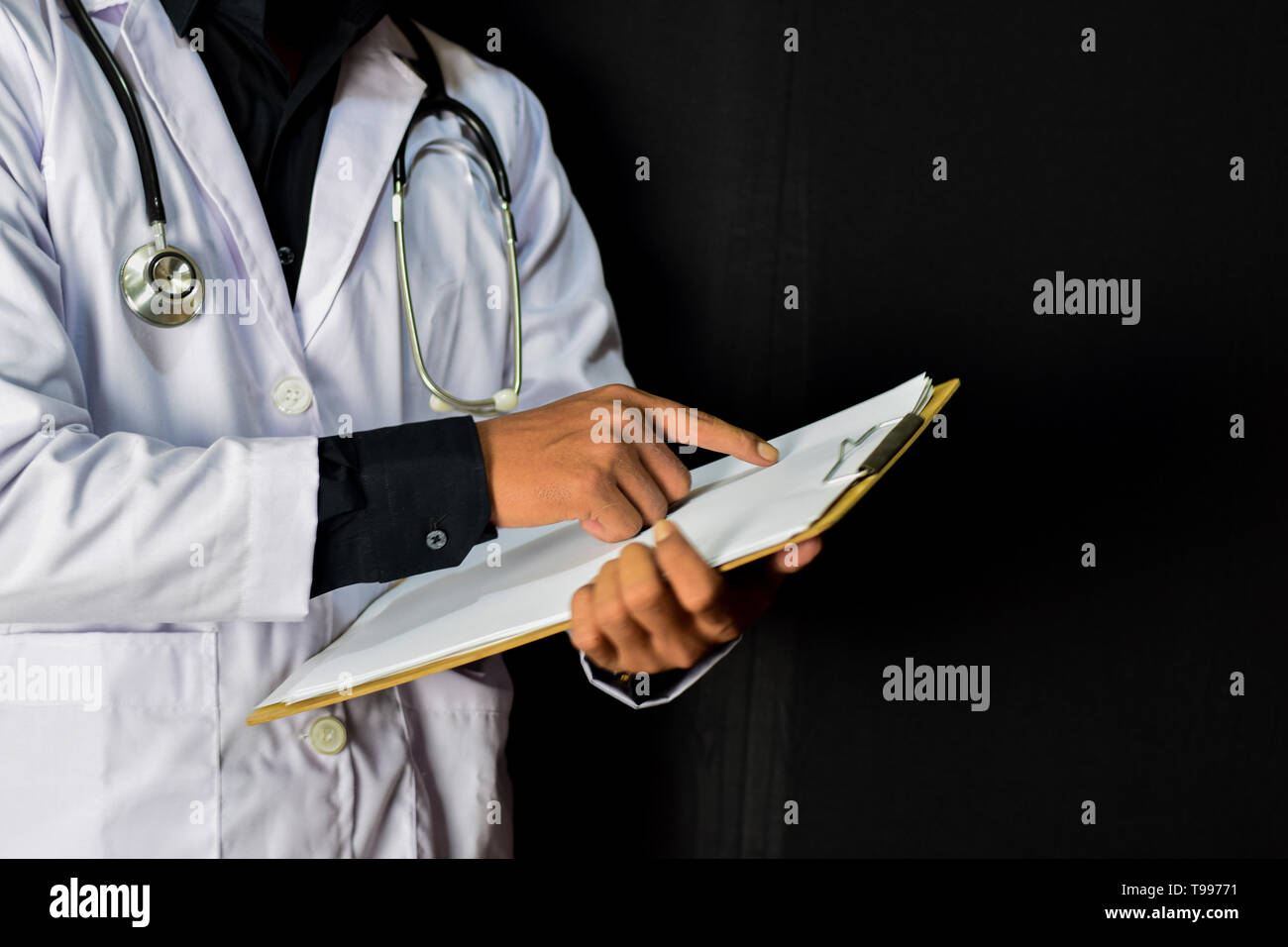 doctor standing holding clipboard on black background. Medical and ...
