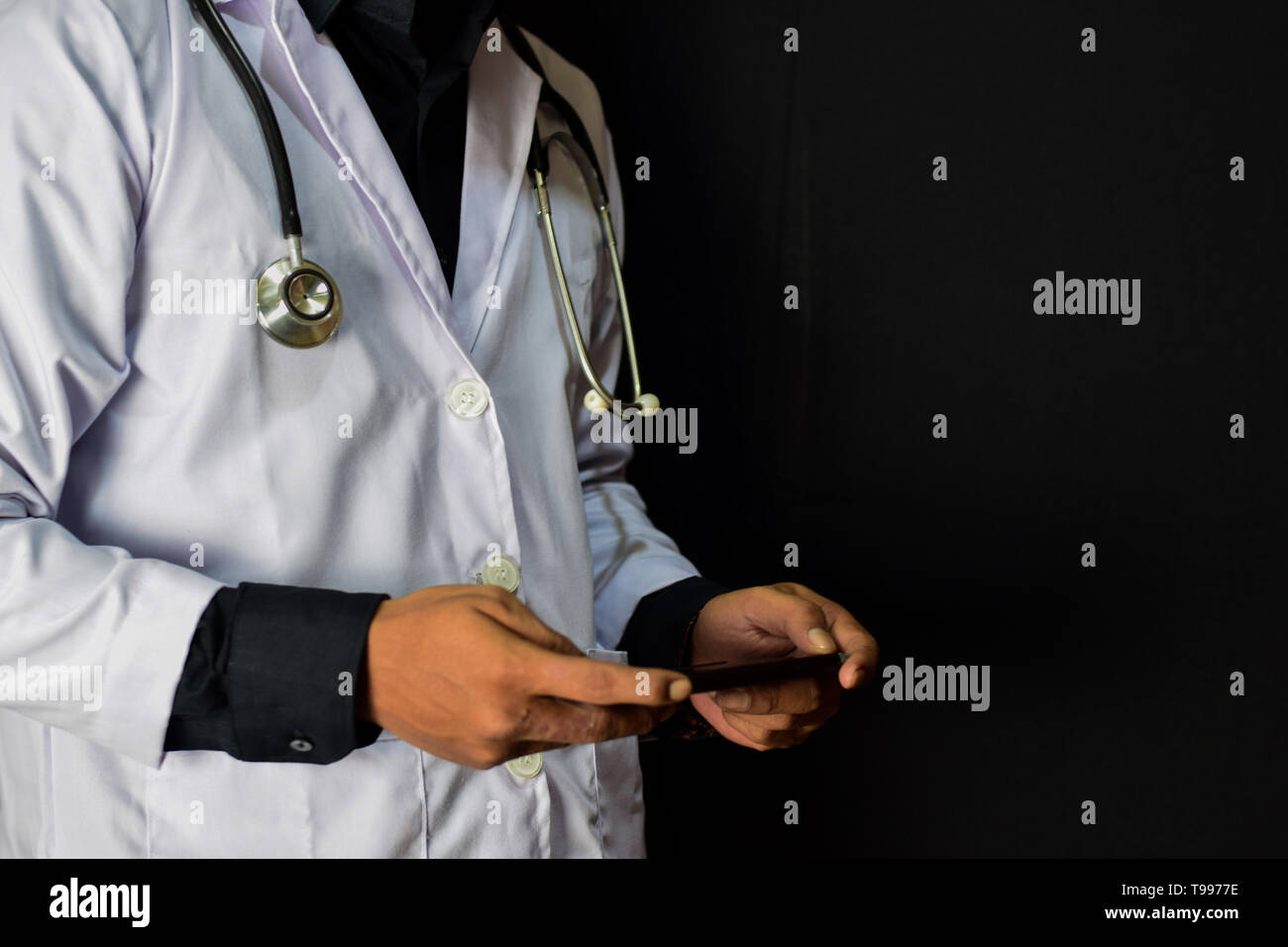 doctor standing holding smartphone on black background. Medical and ...
