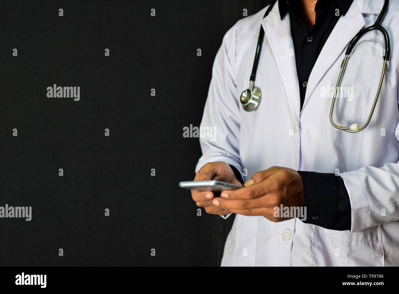 doctor standing holding smartphone on black background. Medical and ...