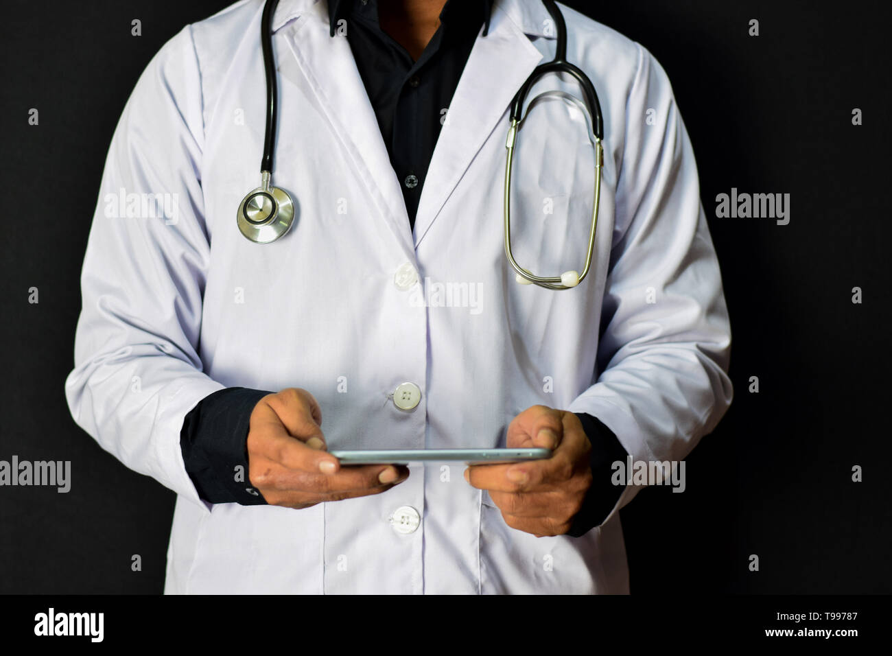 doctor standing holding smartphone on black background. Medical and ...