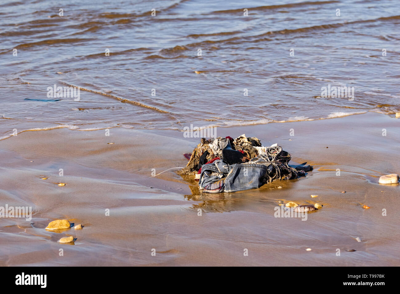 Clothes and rubbish washed up onto sand beach by the Atlantic Ocean ...