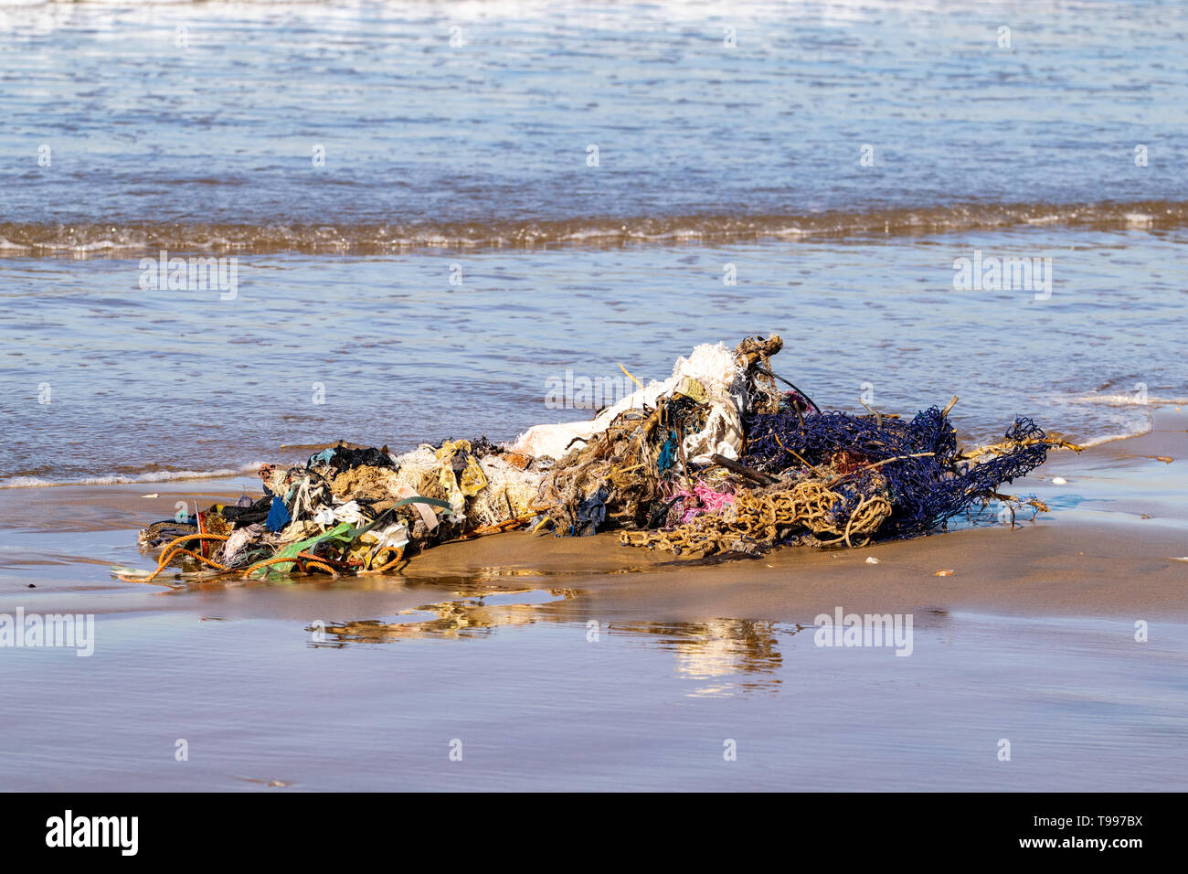 Clothes and rubbish washed up onto sand beach by the Atlantic Ocean ...
