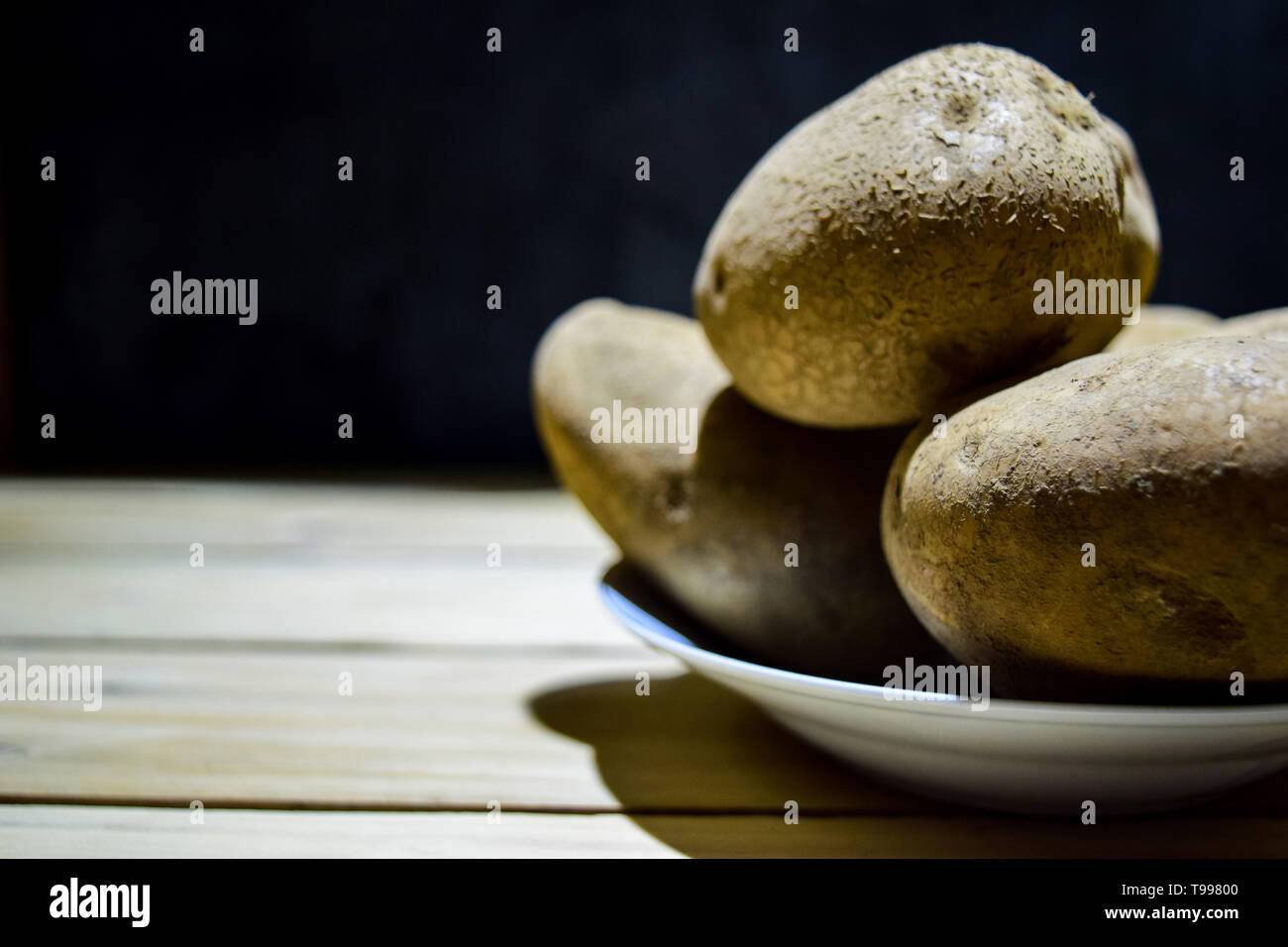 Close-up Fresh potatoes lying on wooden table Stock Photo - Alamy