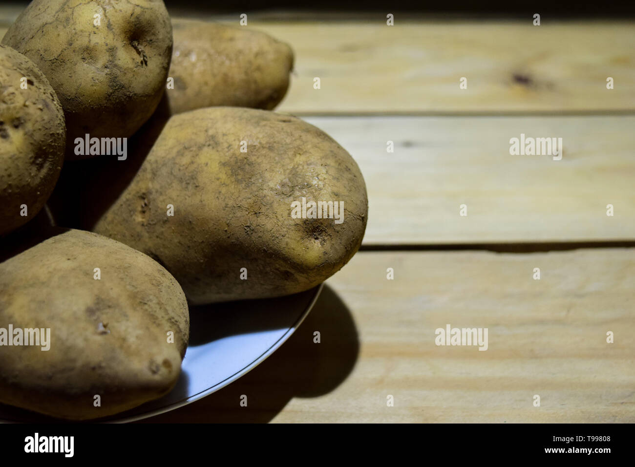 Close-up Fresh potatoes lying on wooden table Stock Photo - Alamy