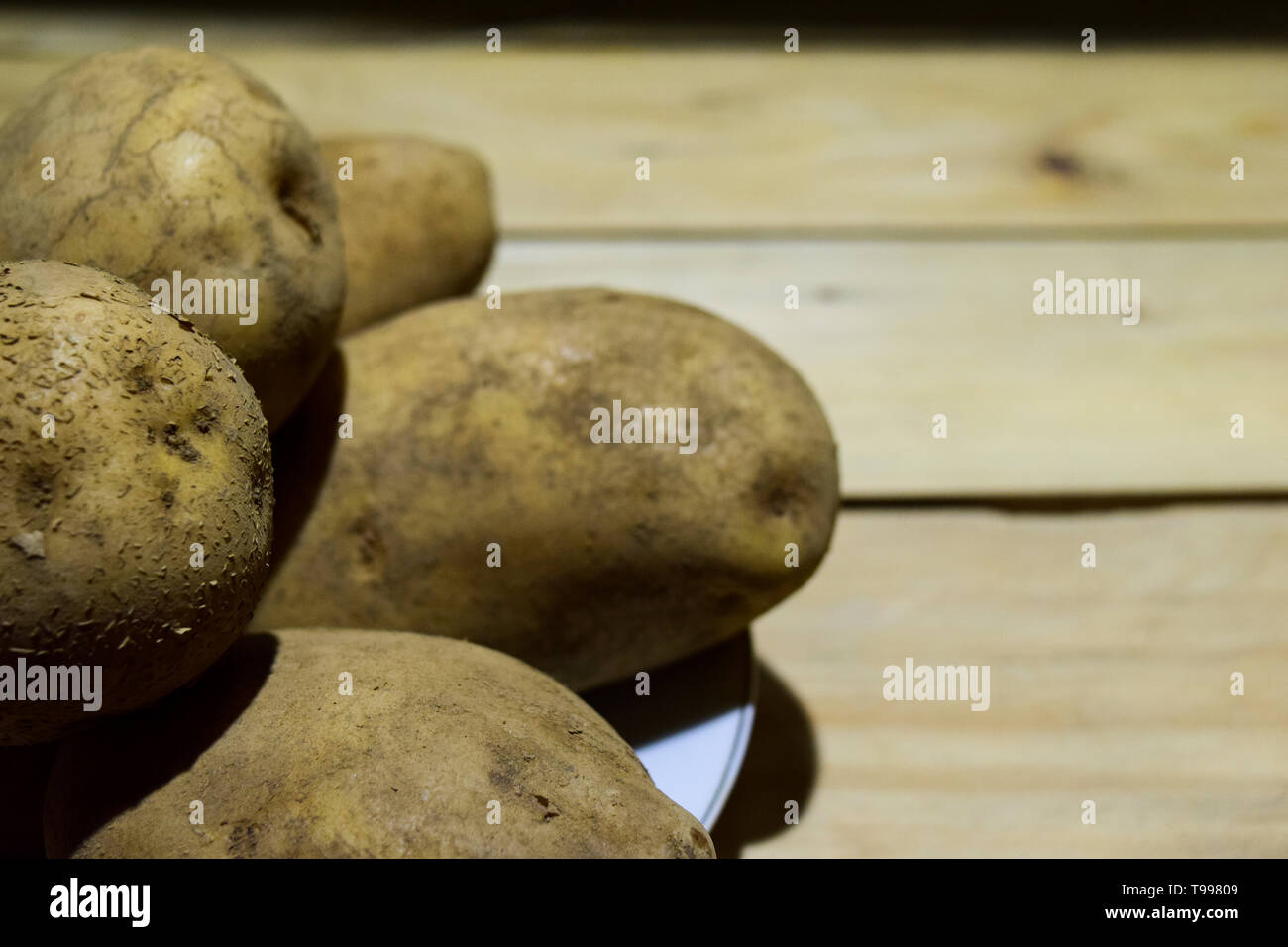 Close-up Fresh potatoes lying on wooden table Stock Photo - Alamy