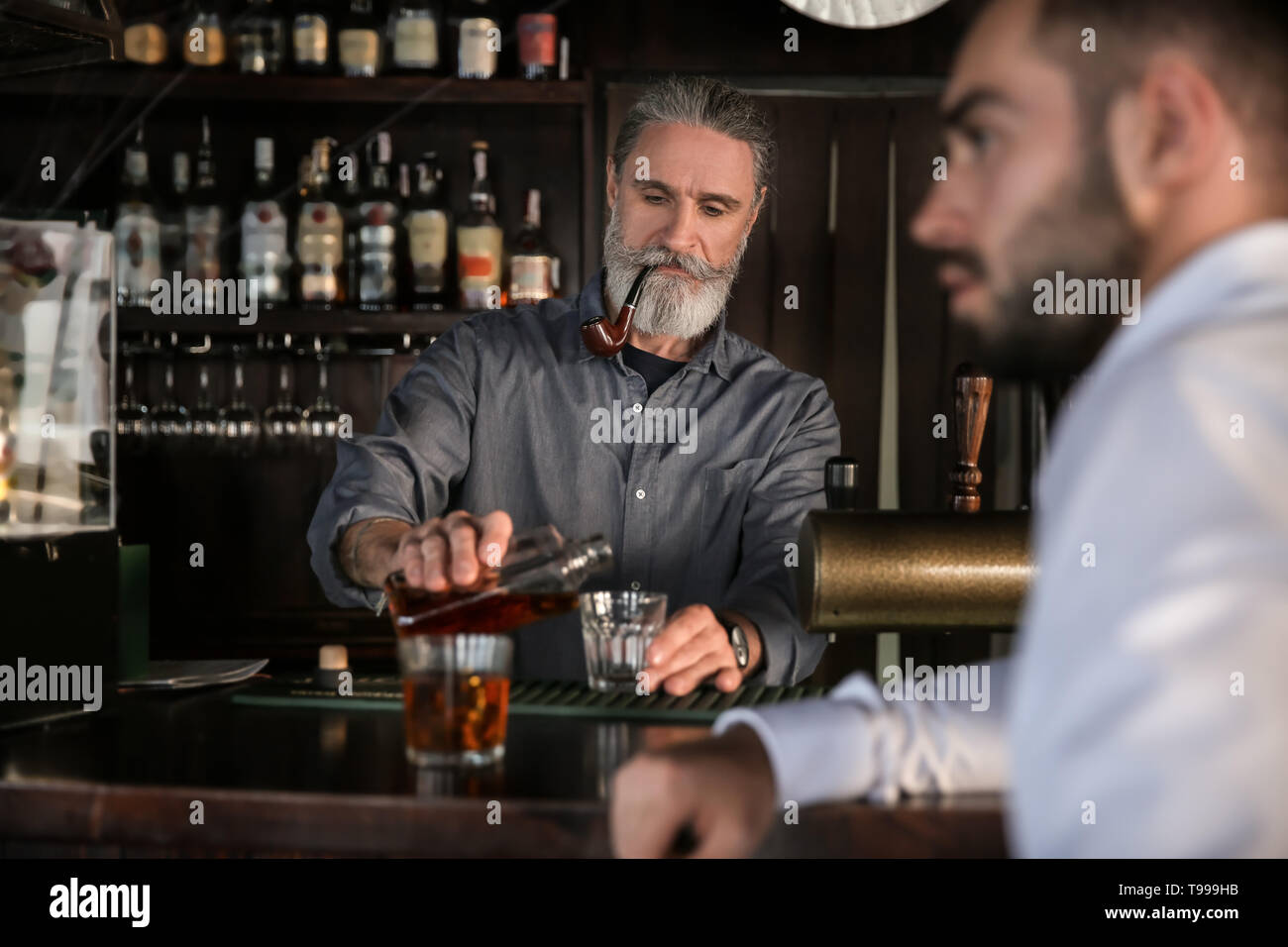 Senior barman serving client in pub Stock Photo - Alamy