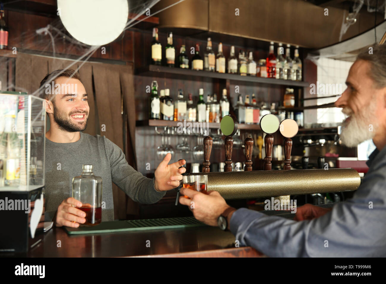 Young barman serving client in pub Stock Photo - Alamy