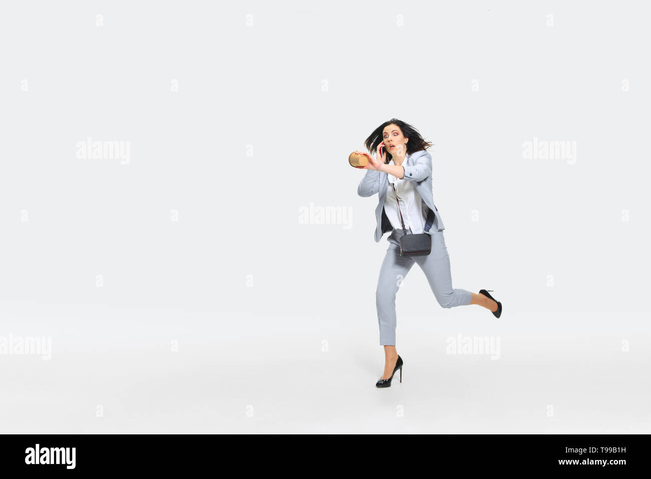 One moment. Young woman in gray suit comes late for work while talking ...