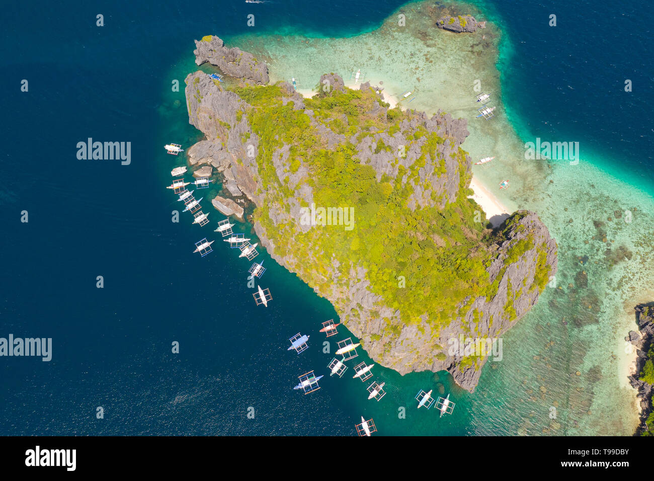 Tropical island with white beach and coral reef.Tourist boats near the ...