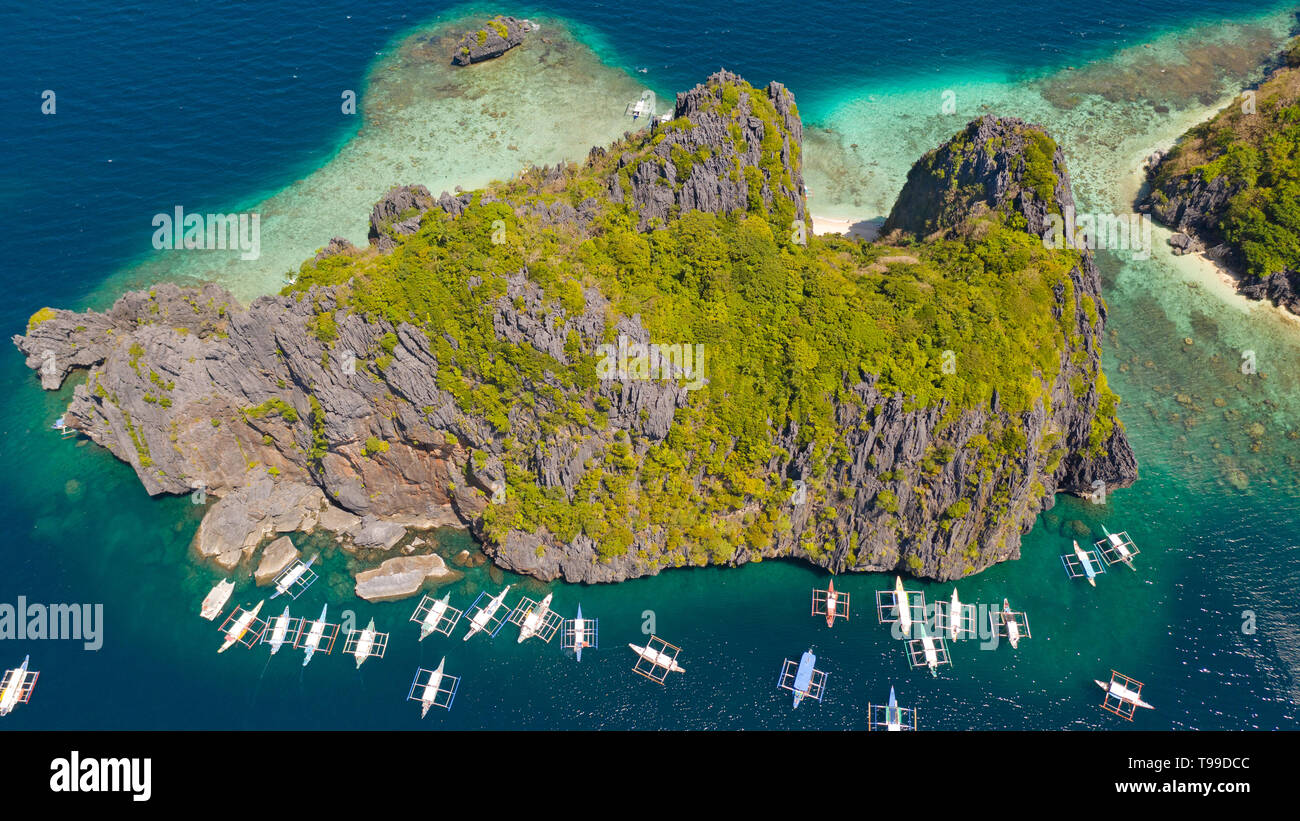 Tropical island with white beach and coral reef.Tourist boats near the ...