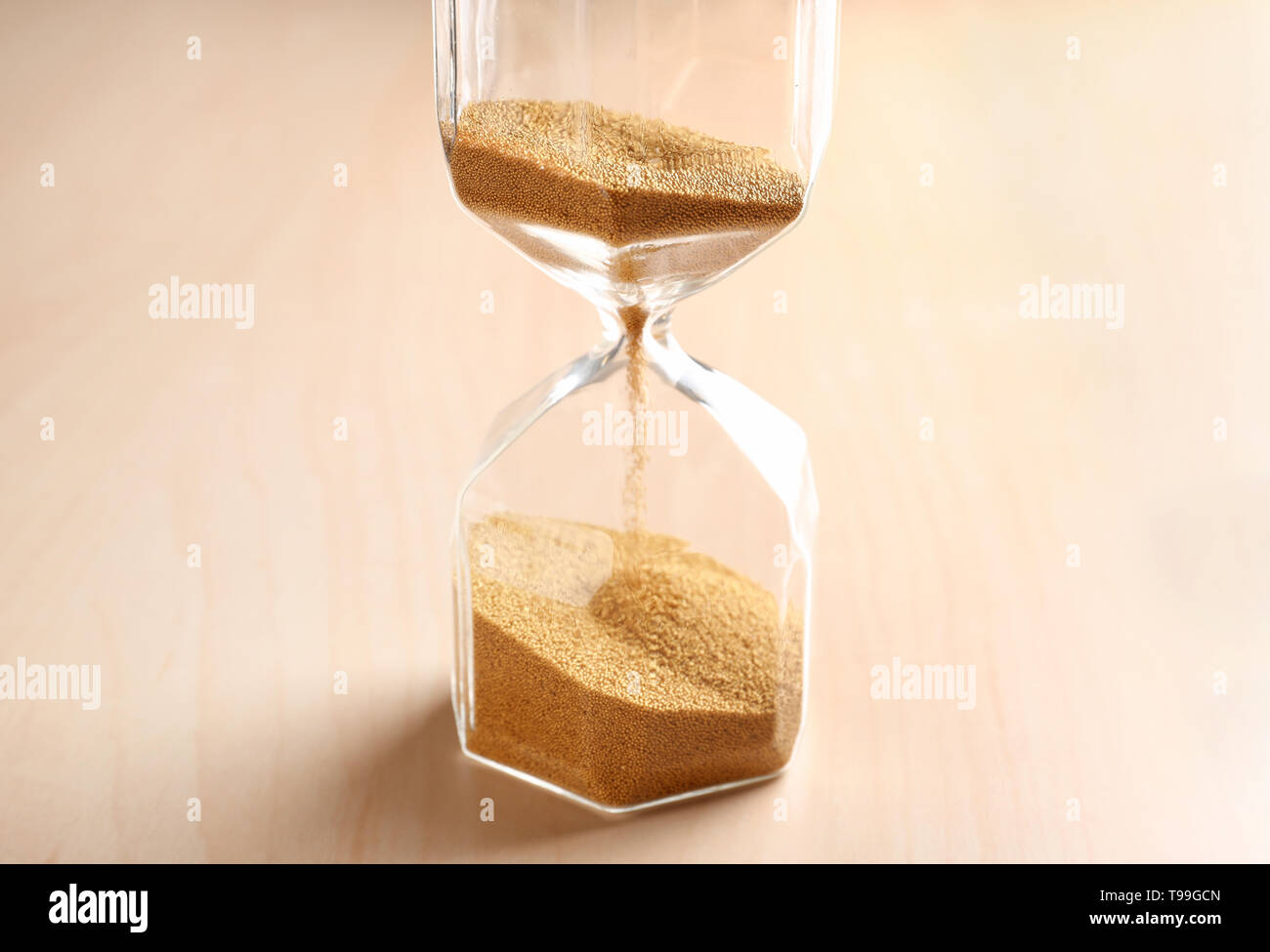 Crystal hourglass with falling sand on wooden table. Deadline concept ...