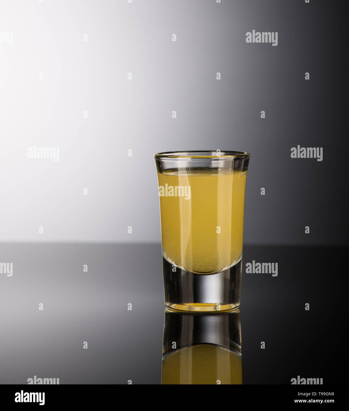 yellow alcoholic liquor in a shot glass isolated on dark background ...