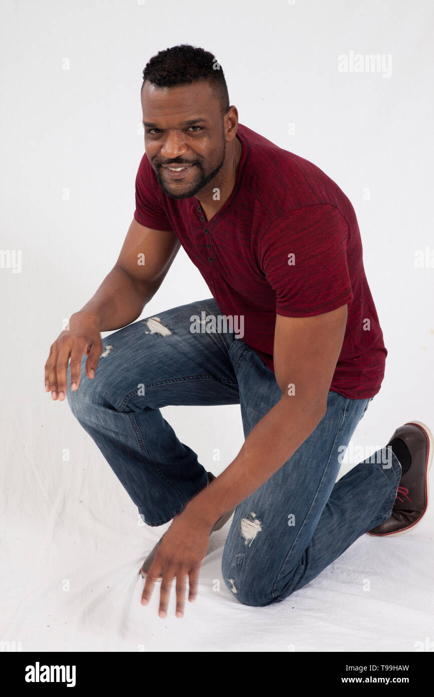 Happy black man kneeling Stock Photo - Alamy