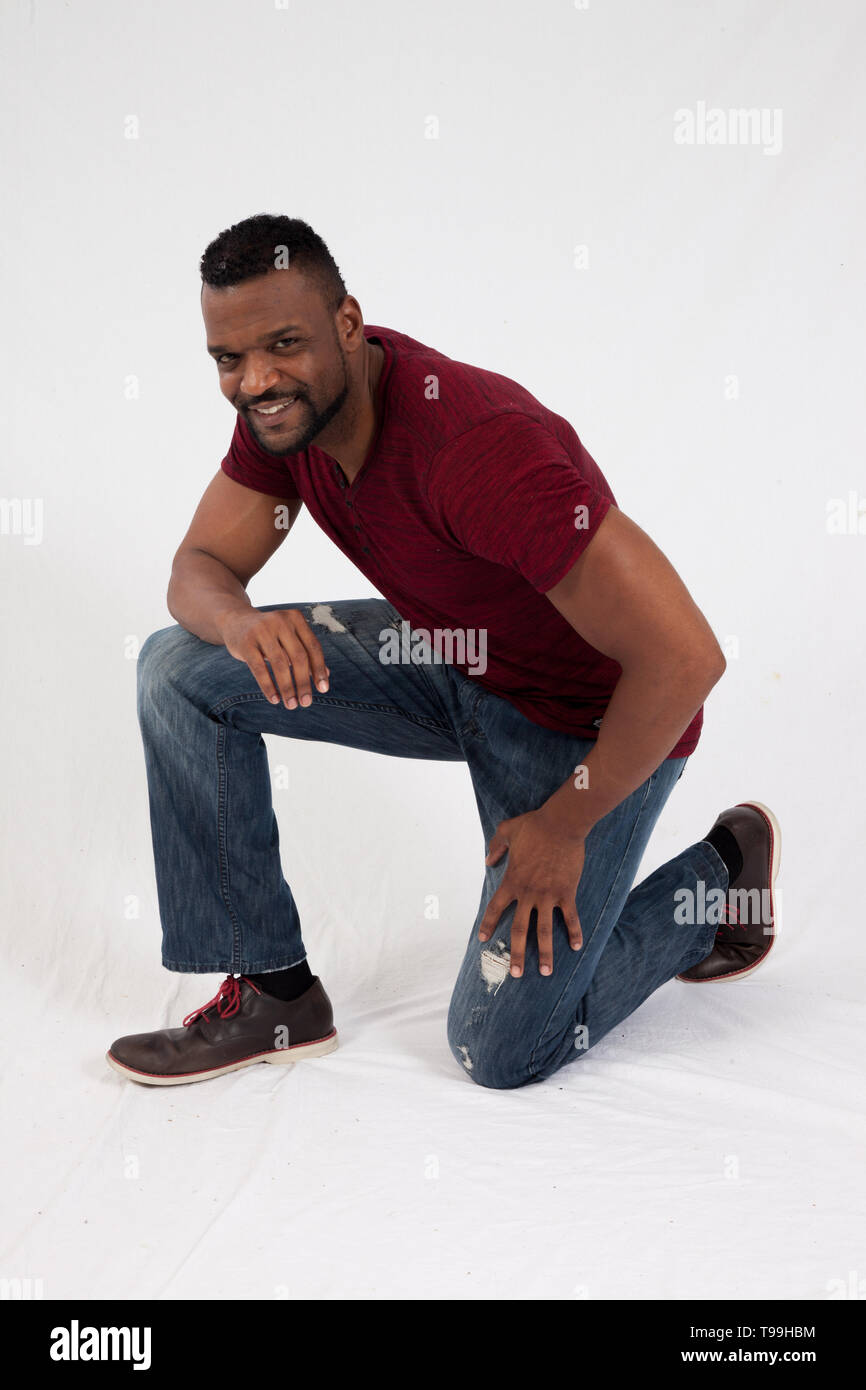 Happy black man kneeling Stock Photo - Alamy