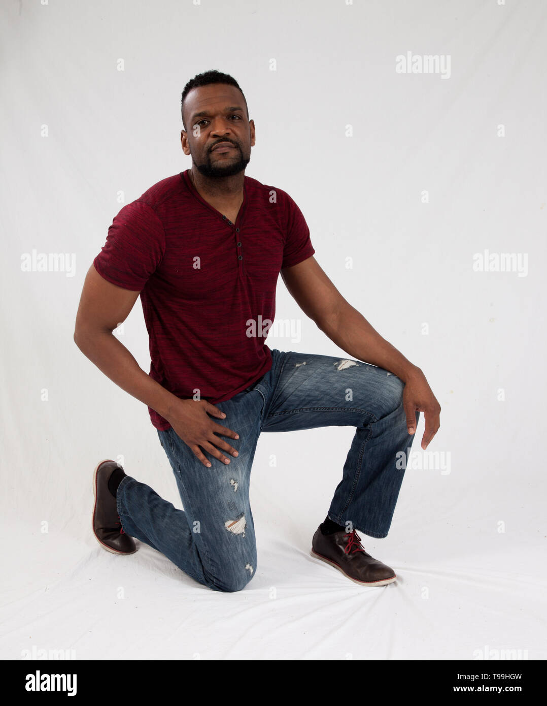 Thoughtful Black man kneeling Stock Photo - Alamy