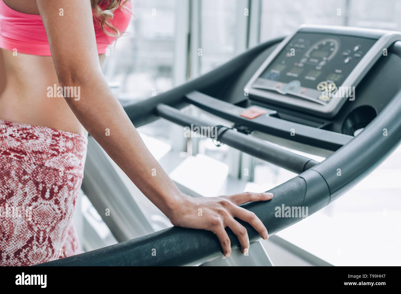 Attractive muscular smiling fitness woman running on treadmill in ...