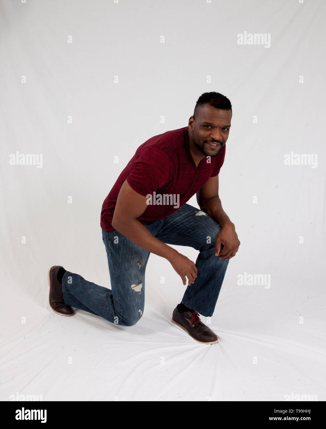 Happy black man kneeling Stock Photo - Alamy