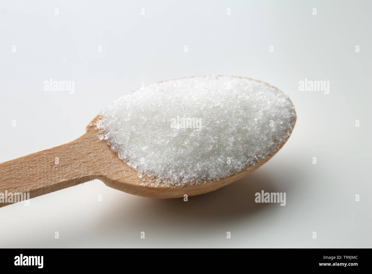 Granulated sugar in wooden spoon on white background Stock Photo - Alamy