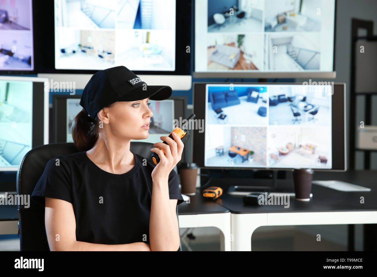 Security guard with portable radio transmitter in surveillance room ...