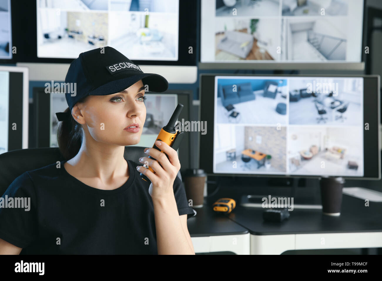 Security guard with portable radio transmitter in surveillance room ...