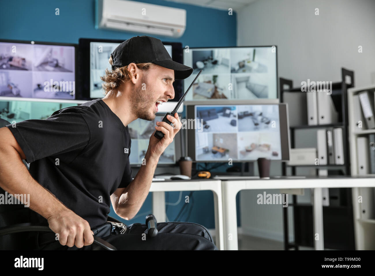Security guard with portable radio transmitter in surveillance room ...