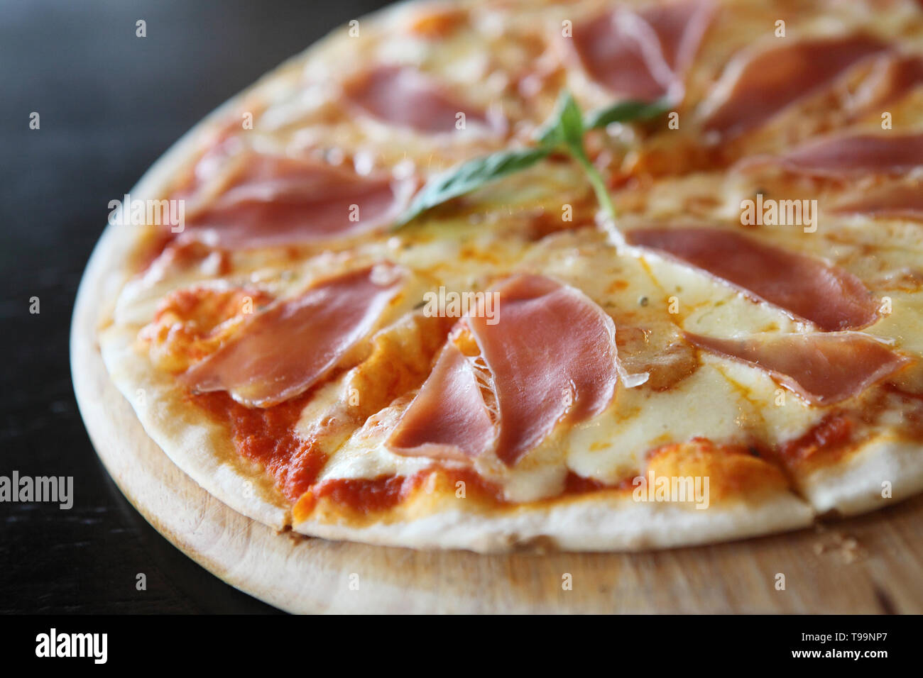 Pizza with dry cured ham and basil Stock Photo - Alamy