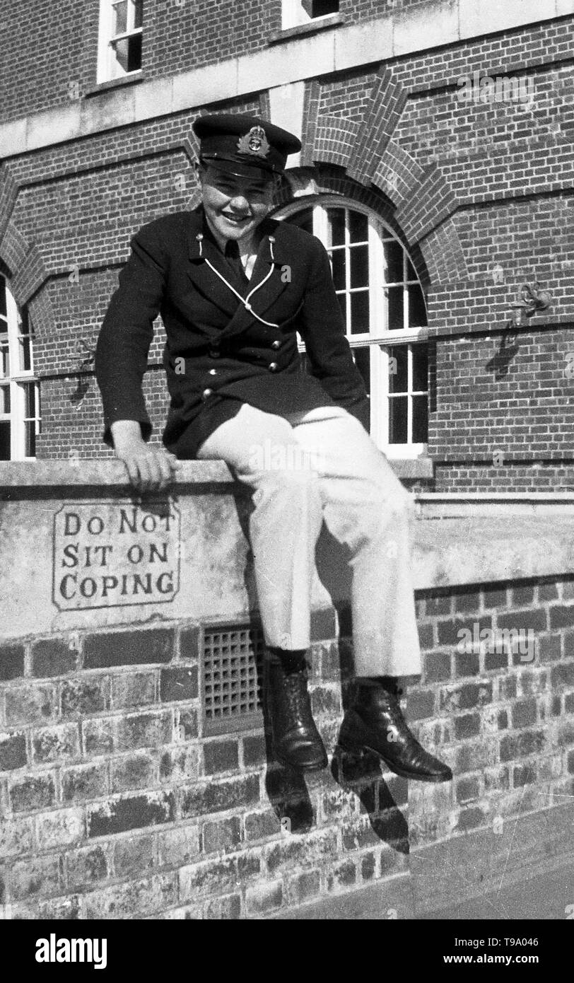 A Boy in Smart Uniform Breaking The Rules by sitting on a wall by a ...