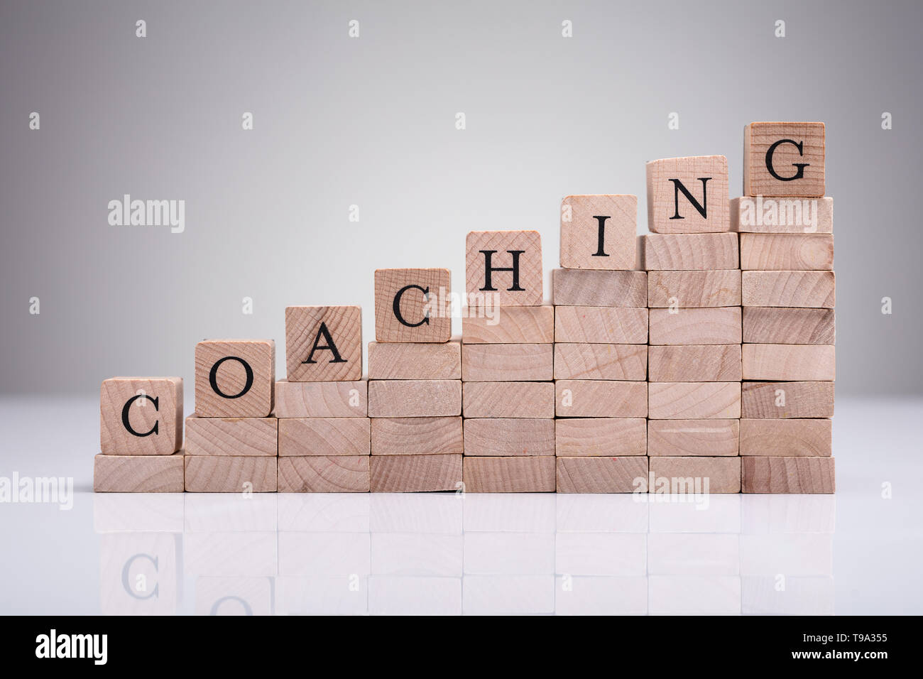 Close-up Of Coaching Word On Wooden Blocks Over Reflective Desk Stock ...