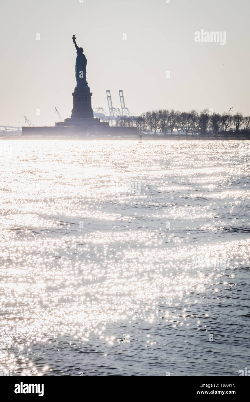 Statue of Liberty shape against the light from Lower Manhattan in New ...