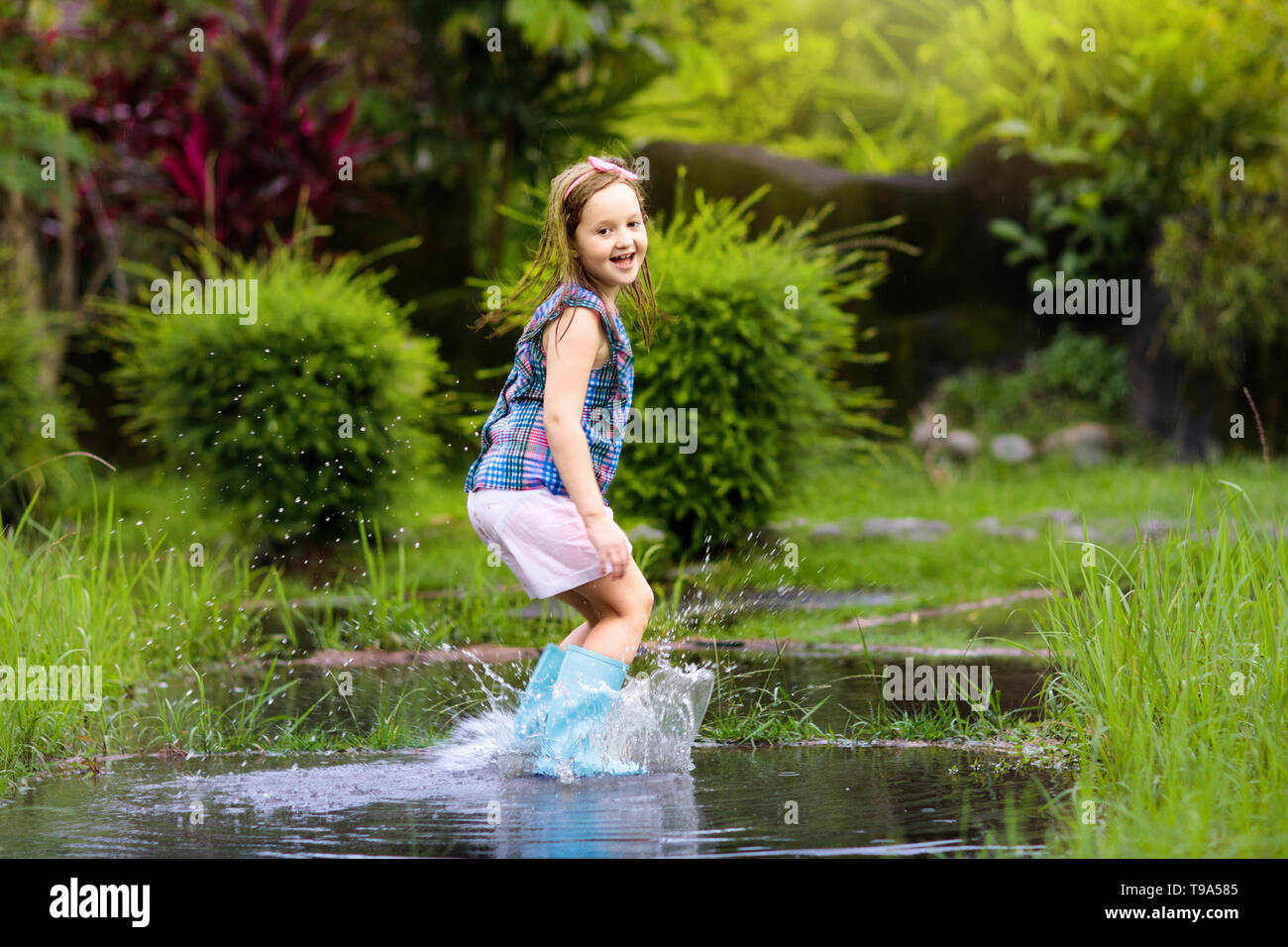 Kid playing out in the rain. Children with umbrella and rain boots play ...