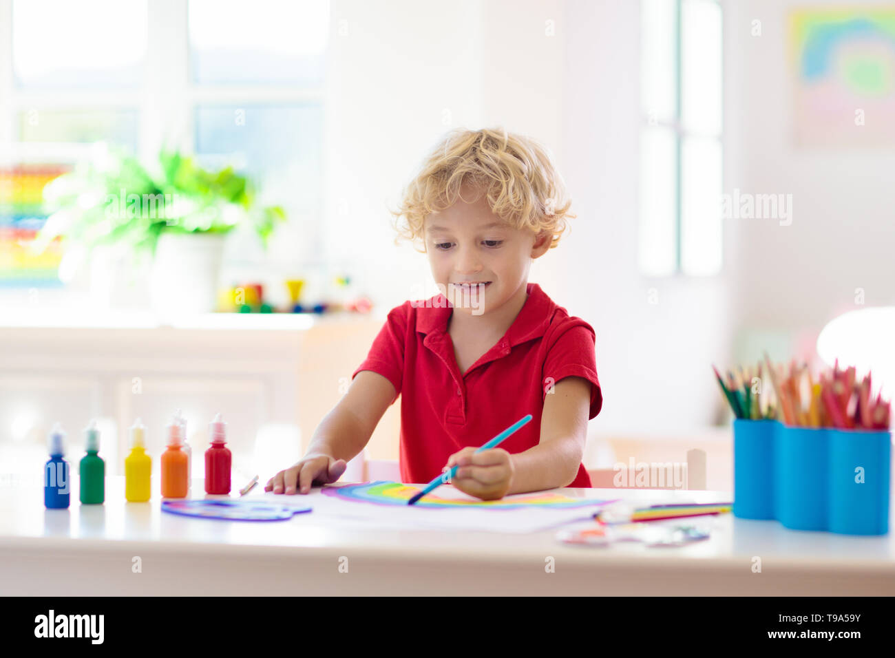Kids paint. Child painting in white sunny study room. Little boy ...