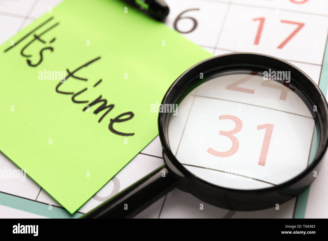 Paper sheet with text IT'S TIME and magnifying glass on calendar ...