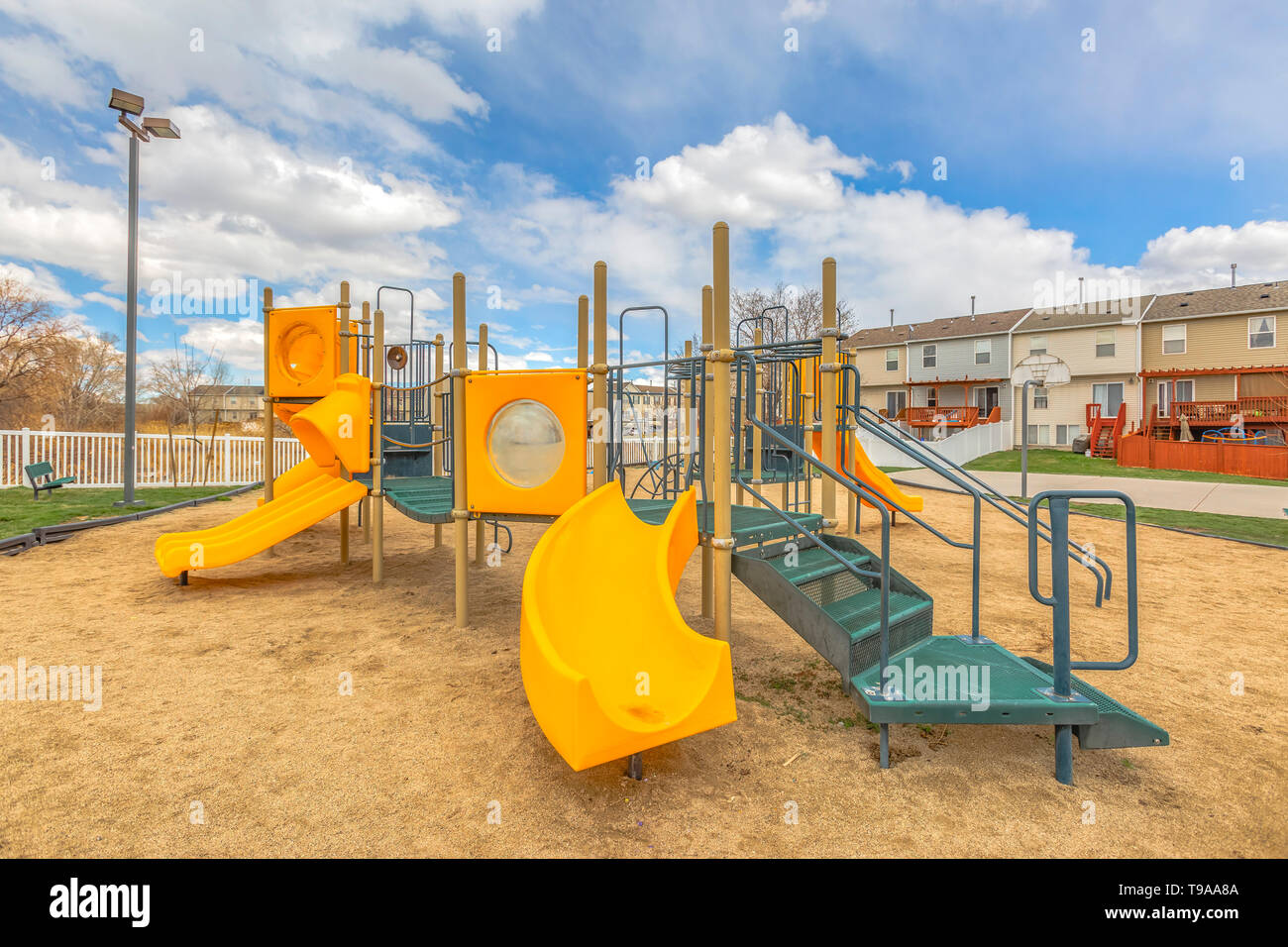 Playground with a bright yellow slide under the vivid sky with puffy ...