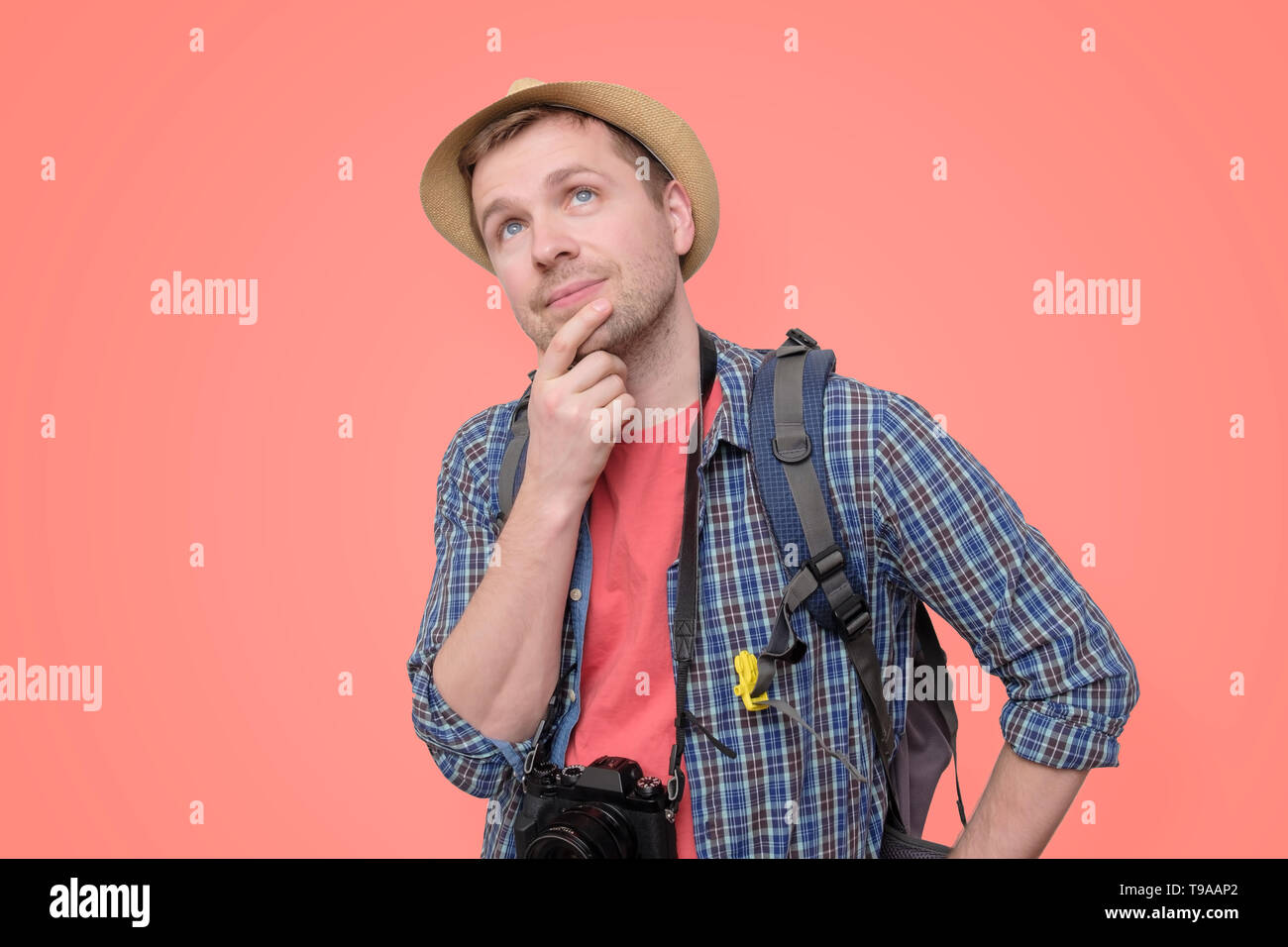 Tourist in hat with camera and backpack thinking Stock Photo - Alamy