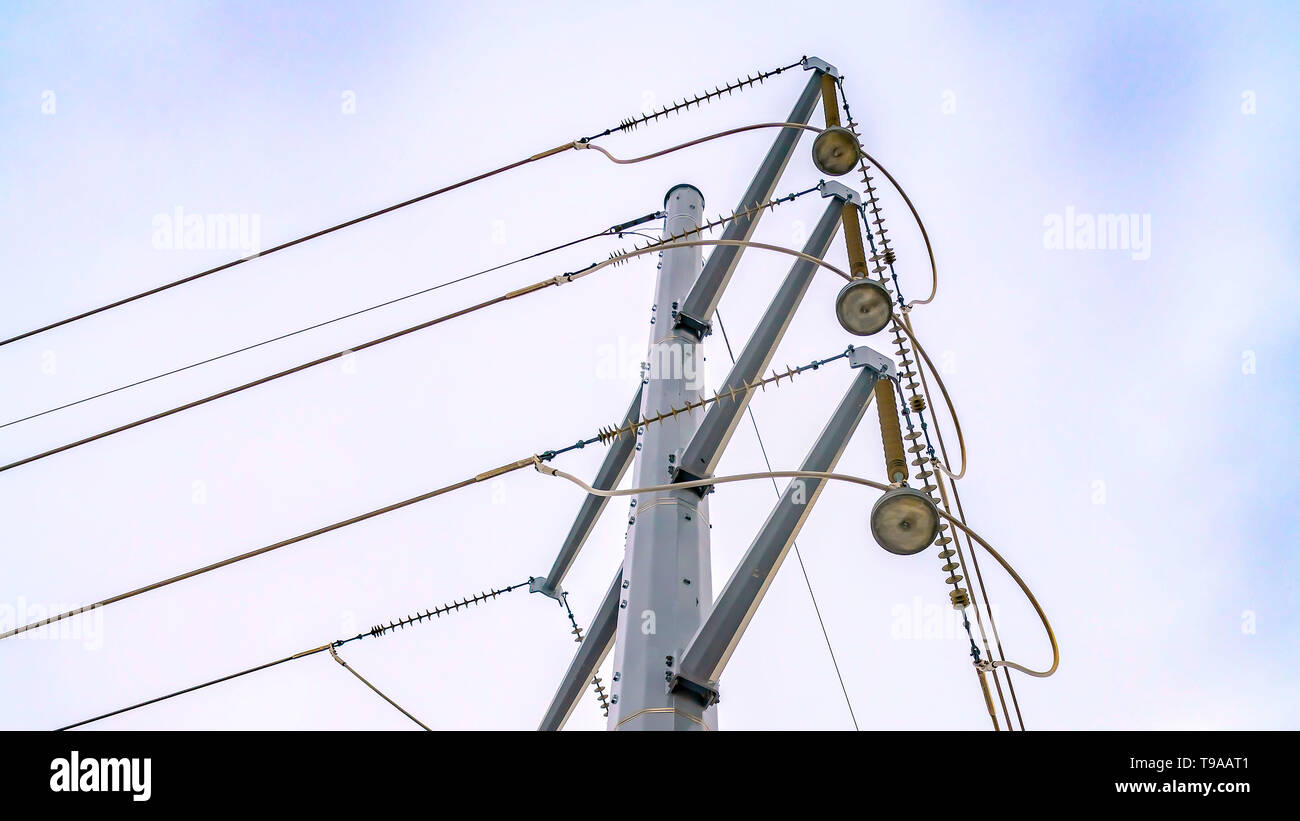 Panorama Looking up at a towering metal post supporting overhead power ...