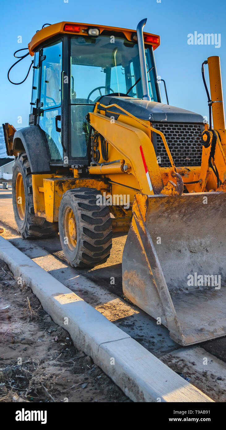 Vertical Yellow loader with homes and mountain against blue sky in the ...