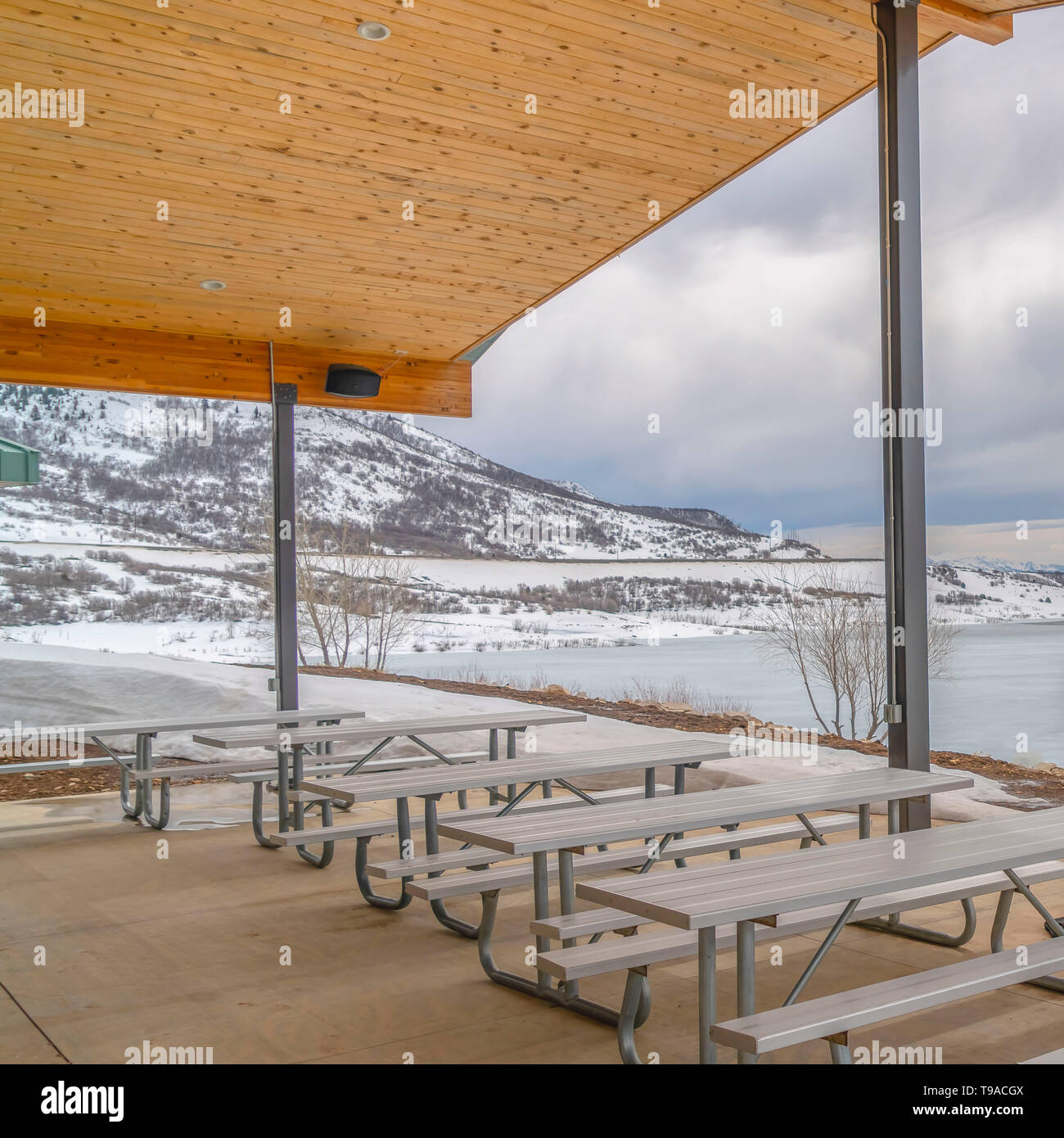 Square Eating area inside a pavilion overlooking a lake amid the snowy ...